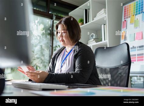 Graphic Designer Analyzing Project Materials In A Contemporary Office Workspace With Focused