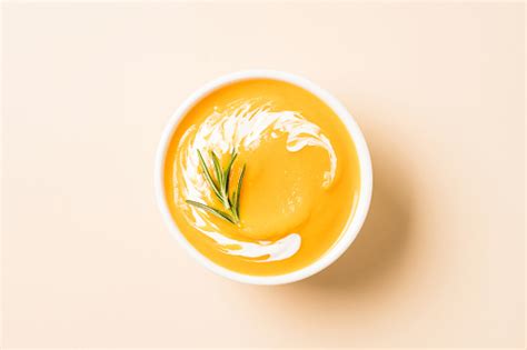 밝은 배경 위에 헤비 크림과 로즈마리로 장식된 흰색 그릇에 담긴 두꺼운 버터넛 스쿼시 비스크 호박과 당근 크림 수프 한 그릇 오버헤드 보기 선택적 초점 수프에 대한 스톡