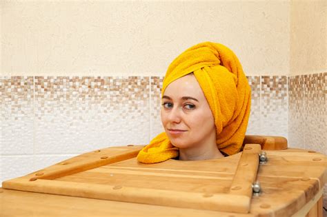 그녀의 머리에 노란색 수건으로 난방 및 건강 개선 절차 동안 삼나무 배럴 사우나에서 백인 외관의 젊은 아름다운 소녀 건강 및 미용 건강관리와 의술에 대한 스톡 사진 및 기타