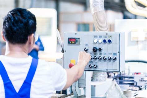 Premium Photo Worker Pressing Buttons On Cnc Machine Control Board In Asian Factory