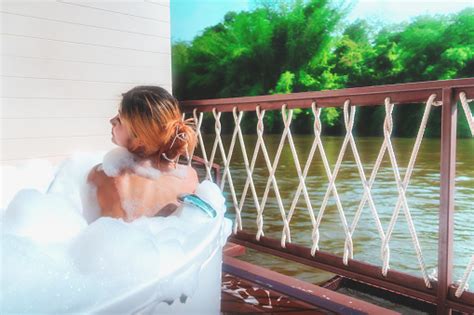 아시아 여성은 자연 강과 숲 배경이있는 발코니에서 거품으로 목욕을하고 있습니다 25 29세에 대한 스톡 사진 및 기타 이미지 25 29세 거품 목욕 건강관리와 의술