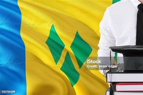 성공적인 학생 교육 개념입니다 세인트 빈센트 그레나딘 국기 배경 위에 책과 졸업 모자를 들고 교사 교육 관련 직업에 대한 스톡 사진 및 기타 이미지 Istock