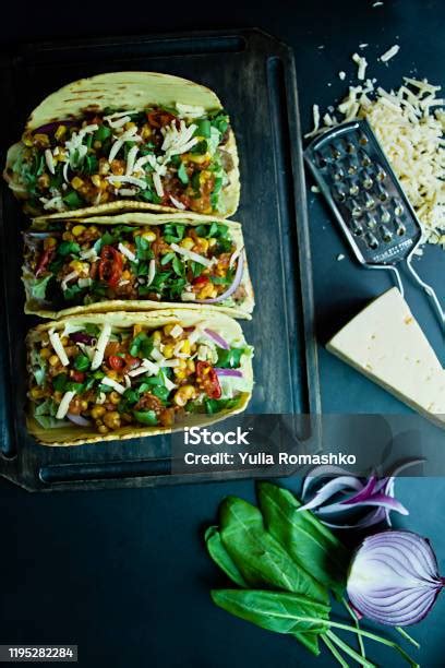 나무 판에 돼지 고기 치즈 옥수수 양파와 허브멕시코 타코의 사진 소스 케첩과 고추 검은 색 배경입니다 측면 뷰 0명에 대한 스톡