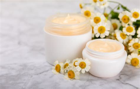밝은 배경에 카모마일 꽃이 있는 얼굴 몸 손을 위한 보습 크림 병을 엽니다 한방 피부과 화장품 위생 크림 천연 화장품 아름다움