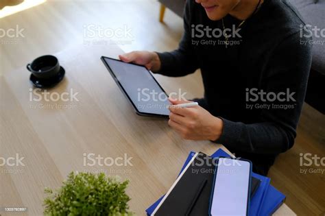 바닥에 앉아있는 동안 디지털 태블릿에 쓰기 스타일러스 펜을 사용하여 젊은 남자의 자른 샷 20 24세에 대한 스톡 사진 및 기타