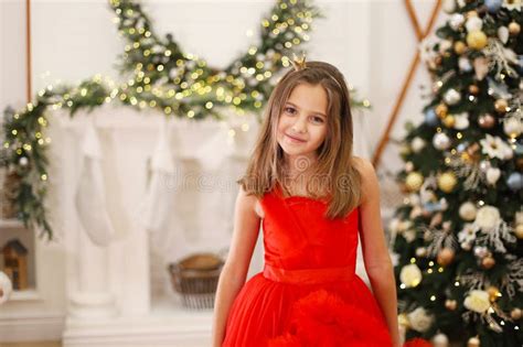 Smiling Girl In Red Dress By Christmas Tree A Young Girl Wearing A Red