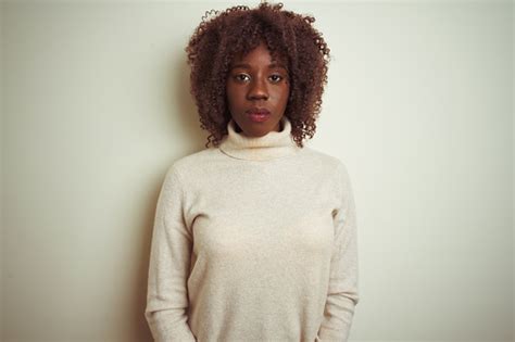 얼굴에 심각한 표정으로 고립 된 흰색 배경 위에 터틀넥 스웨터를 입은 젊은 아프리카 아프로 여성 카메라를 보는 간단하고 자연스러운 심각한에 대한 스톡 사진 및 기타 이미지