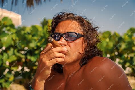 Premium Photo A Man With Long Hair Smokes A Cuban Cigar On The Beach
