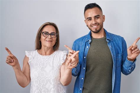 Hispanic Mother And Son Standing Together Smiling Confident Pointing With Fingers To Different