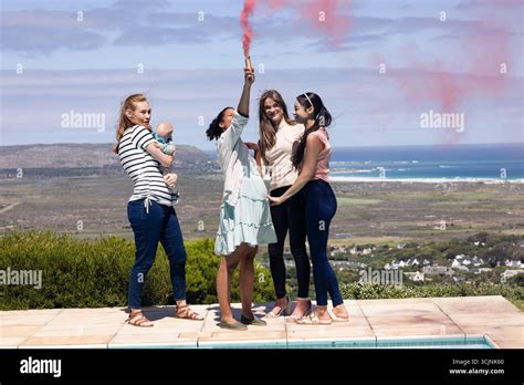 Friends Celebrating With Smoke Flare By Poolside Enjoying Scenic Ocean