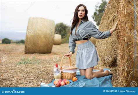 Female Brunette With Long Hair Wearied In Grey Suit Poses Near Haystack