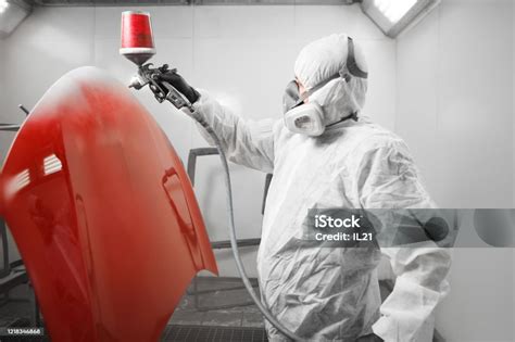 흰색 페인트 챔버에 빨간 자동차 몸 요소를 그리는 에어 브러시 분쇄기와 보호 장갑에 화가 노동자를 스프레이 금속에 대한 스톡
