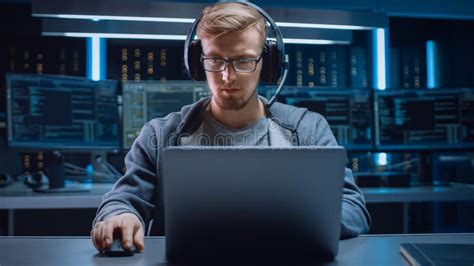 Portrait Of Software Developer Hacker Gamer Wearing Glasses And Headset Sitting At His Desk
