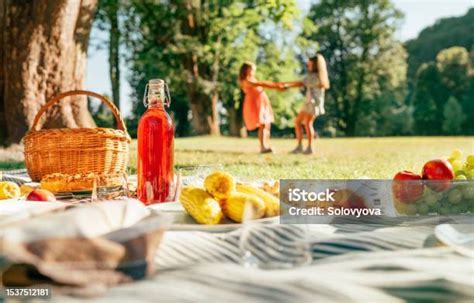 삶은 옥수수 과일 주스 한 병 도시 여름 공원의 바구니 정물화 두 자매 소녀가 손을 잡고 배경을 돌고 있다 가족 가치와 야외 개념 여름에 대한 스톡 사진 및 기타 이미지