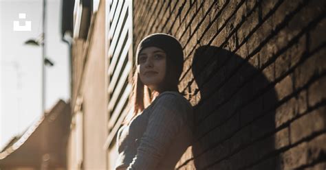 낮 동안 벽돌 벽에 기대어 있는 파란색 티셔츠와 검은 치마를 입은 여자 사진 Unsplash의 무료 의류 이미지