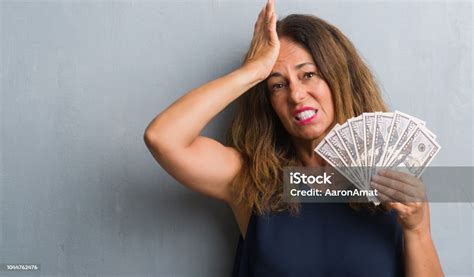 중세 스페인 여자 회색 그런 지 벽 머리에 손으로 압박 하는 달러를 들고 서 충격 수치심과 깜짝 얼굴로 분노와 좌절 두려워 하 고 실수에 대 한 화가 갈색 머리에 대한 스톡