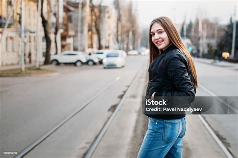 긴 머리 도시 배경 산책 우아한 여자의 뒷면에서 초상화입니다 그녀는 검은 가죽 재킷과 청바지를가지고 있다 그녀는 카메라를 웃 고 있습니다 가을에 대한 스톡 사진 및 기타