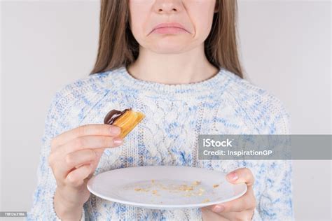 슬픈 여자 Havinf의 자른 클로즈업 사진은 손에 남은 왼쪽 회색 배경에 흰색 접시를 들고 너무 많은 맛있는 디저트를 먹는 후회 죄책감에 대한 스톡 사진 및 기타 이미지