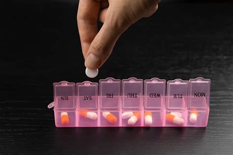 분홍색 필박스에서 알약을 복용하거나 검은 테이블에 매일 약을 먹기 위해 알약과 비타민을 분류하는 여성의 클로즈업 의료 의학의 개념 복사 공간 가정 생활에 대한 스톡 사진 및