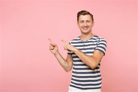 세로 핑크 동향 배경에 고립 된 복사 공간에 줄무늬 T셔츠 포인팅 집게 손가락을 옆으로 입고 웃는 젊은 남자를 흥분 사람들이 진심으 감정 라이프 스타일 개념 광고 영역입니다