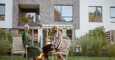 정원에서 홈 파티를 하는 동안 칵테일을 마시는 다인종 커플 바베큐를 위해 불을 태우고 있습니다 관계의 개념 현대 국내 생활