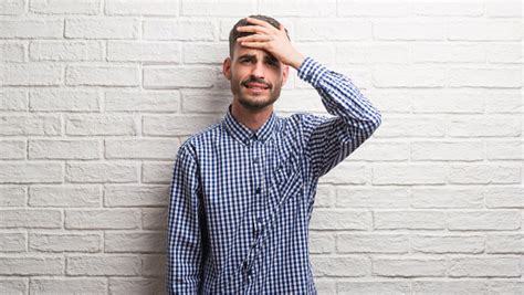 젊은 성인 남자 머리 수치심과 깜짝 얼굴로 충격된에 손으로 압박 흰색 벽돌 벽을 통해 서 분노 하 고 좌절 두려워 하 고 실수에 대 한 화가 감정에 대한 스톡 사진 및 기타