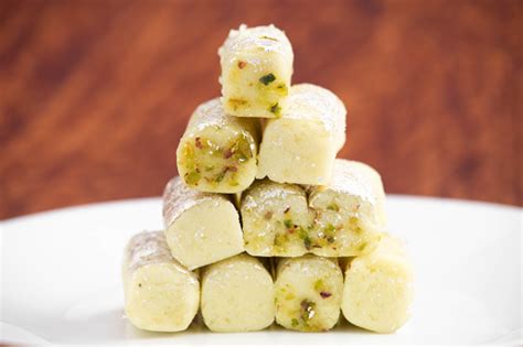 카주 피스타 롤 또는 캐슈 피스타치오 롤미타이는 데시 기버터의 무너진 코야 마와 케사르 마바 엘라이치 코아와 아몬드와 드라이 과일을 곁들인 간 캐슈로 만들어집니다 갈색