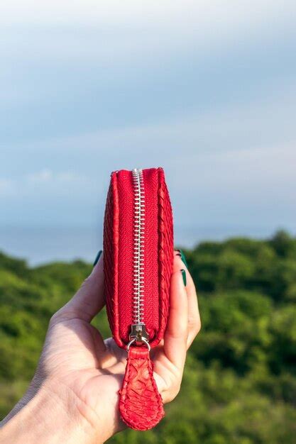 Premium Photo A Girl On A Background Of Tropical Trees Holds A Purse Made Of Python Skin