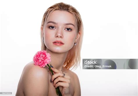 분홍색 꽃과 매력적인 젊은 여자 금발 모델 흰색 배경에 고립 된 얼굴에 가까운 분홍색 꽃을 들고 미용 및 건강 관리 무료 공간의