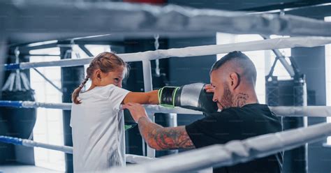 권투 링에서 서로 스파링을합니다 젊은 문신을 한 권투 코치는 체육관에서 귀여운 소녀를 가르칩니다 사진 Unsplash의