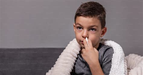 아이는 독감에 걸렸고 비강 스프레이를 사용하여 자신을 돕고 있습니다 비강 스프레이를 사용하는 소년 감기에 도움이되는 비강 스프레이 코가 뚝뚝 떨어지는 비염 어린