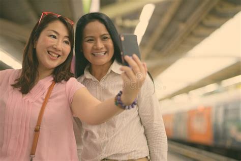 Two Mature Asian Women Together At The Skytrain Station In Bangkok