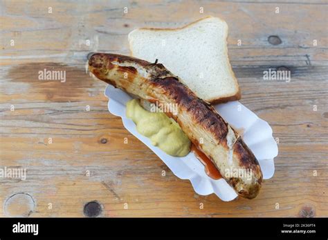 Roasted Sausage Or German Bratwurst On A Paper Plate With Mustard And
