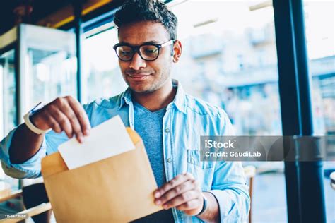 트렌디 한 안경 에 성숙한 지능형 남성 의 자른 이미지 종이 를 넣어 종이 를 넣어 밝은 갈색 봉투 에 보낼 수 있습니다 잘 생긴 긍정적인 남자 복용 편지 서 동안 앉아