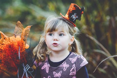 마녀로 옷을 입은 어린 유아 소녀의 초상화가 할로윈을 축하합니다 오렌지 재미 모자와 마녀 빗자루를 잡고 야외에서 행복한 아이 10 월에 아름 다운 가족 축제 시즌 야외 활동