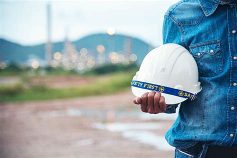 엔지니어 남자 손 은 토목 건설 공학에 대한 하드 햇 흰색 작업 헬멧 하드 모자를 들고 안전 복을 입은 건설 엔지니어 남자가 건설 현장에서 화이트 워크 헬멧 하드 햇을 손에