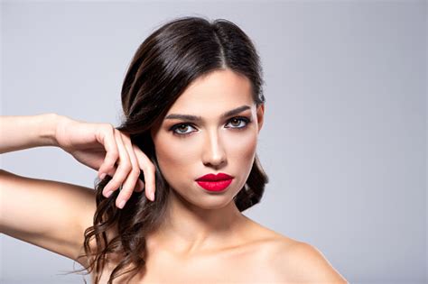 빨간 립스틱과 아름다운 젊은 패션 여성 얼굴의 깨끗한 피부를 가진 갈색 머리 여자 밝은 빨간 입술모델의 초상화 스튜디오에서 포즈를 취하는 밝은 광택 메이크업과 매력적인 패션