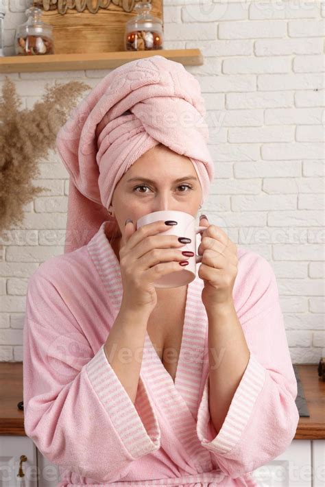 Woman In Bathrobe After Shower Drinks Coffee For Breakfast At Home