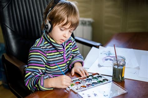 금발의 유아 아기 소년은 집에서 음악을 듣고 그림을 그립니다 아이는 수채화 물감으로 활동 시간을 갖습니다 가정 생활에 대한 스톡