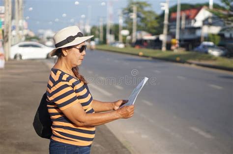 Asian Woman Tourist Is Standing At The Footpath Looking At The Map