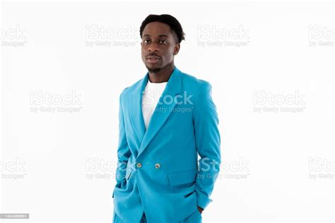 Serios 아프리카계 미국인 남자는 아름다운 파란색 스마트 의상을 입고 주머니에 팔을 들고 카메라를 보고 격리된 스튜디오에서 흰색 배경에 포즈를 취하고 있습니다 갈색에