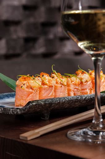 연어 라임 껍질 참깨 토비코 캐비어 소스를 곁들인 롤과 와인 한 잔과 대나무 젓가락이 있는 테이블 위의 대리석 접시에 담겨 있습니다 0명에 대한 스톡 사진 및 기타 이미지