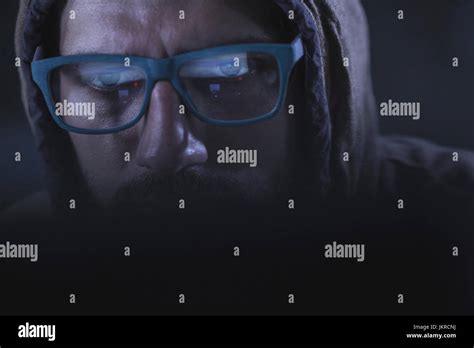 close up of serious computer hacker wearing eyeglasses and hood stock