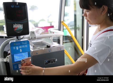 A Passenger Scans A QR Code Of The Electronic Bus Card On Her Smartphone To Pay For Bus Fees On