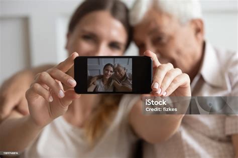 행복한 아버지와 함께 휴대 전화로 사진을 찍는 미소 짓는 여자 2명에 대한 스톡 사진 및 기타 이미지 2명 80 89세