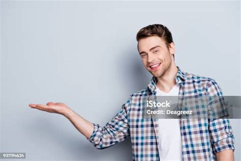 제시 하는 새로운 제품 시동 회색 배경 위에 서 서 그의 손바닥에 복사 공간을 보여주는 성공 쾌활 한 귀여운 전문 젊은 남자의