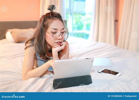 Beautiful And Woman Using Laptop Computer And Listening To Music From Tablet On Bed Stock Photo