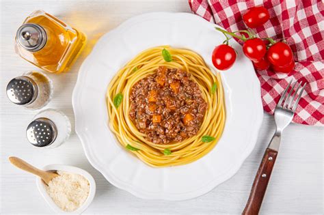 볼로냐 소스 파스타입니다 에 백색 격판덮개 파 르 마 치즈 토마토 올리브 오일의 분기와 포크 배경은 흰색 이다 이탈리아