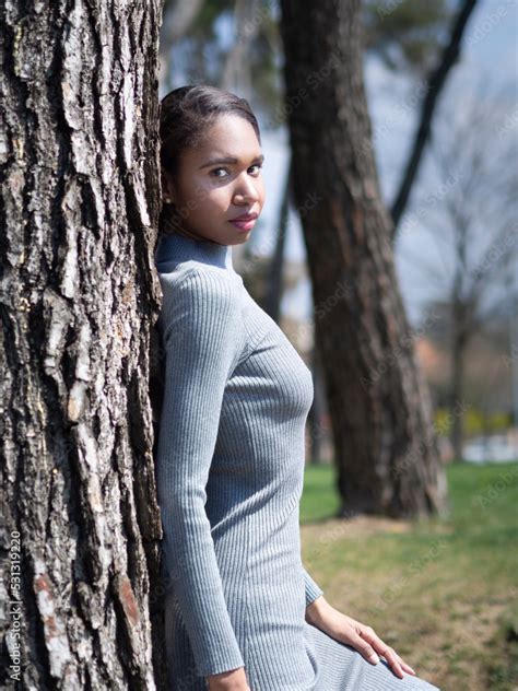 Mujer Colombiana Joven De Color Mulata Apoyada Con La Espalda En Un Tronco Mirando Al Frente