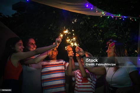 테라스에서 불꽃놀이와 함께 파티를 만드는 다양 한 사람들의 그룹 가족 생일을 축하하는 스파클러를 즐기며 함께 즐거운 시간을 보내는 소녀와 소년 청소년 행복과 휴일 개념